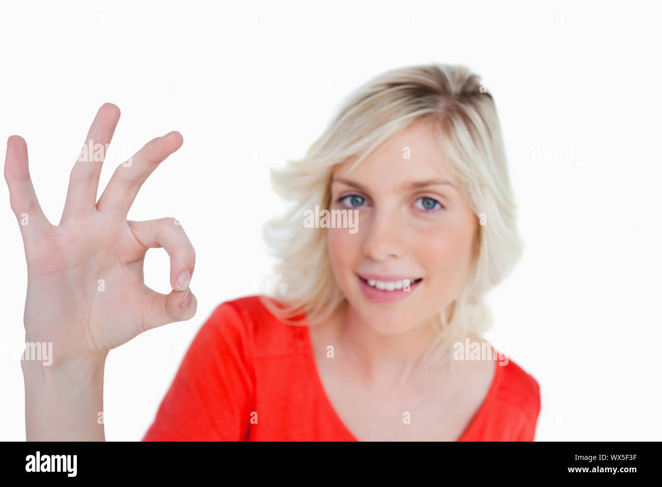 Woman showing the OK sign in front of the camera against a white ...