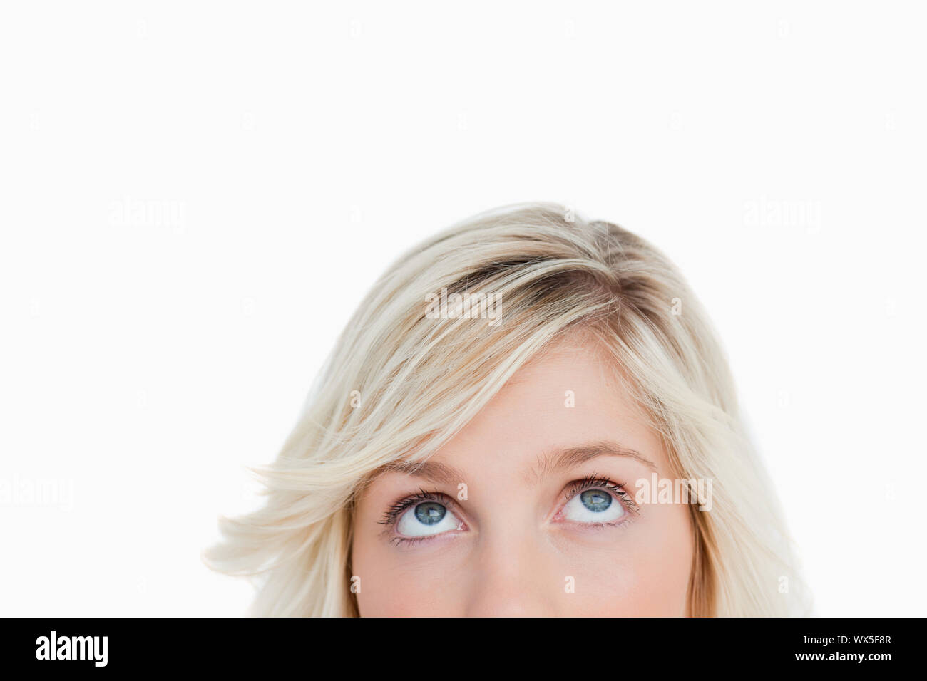 Upper part of the face of a blonde woman looking up against a white ...