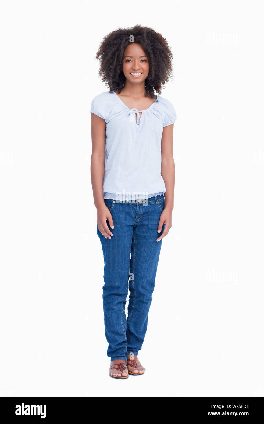 Relaxed young woman standing up with arms by side against a white ...