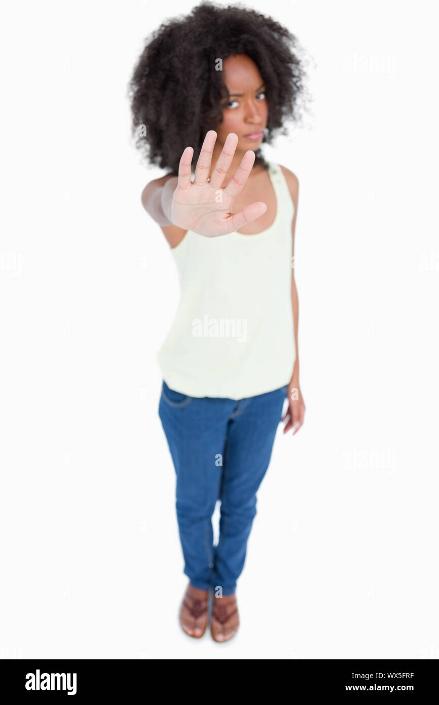 Woman standing up while making the hand stop sign against a white ...