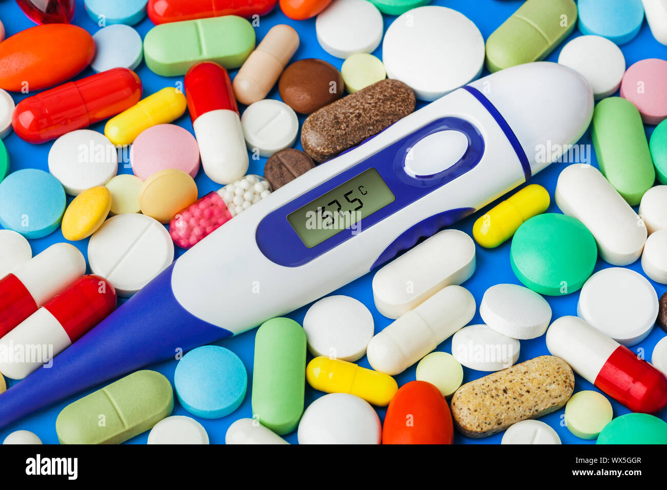 Pills and electronic thermometer (37.5 degrees) - medical background ...