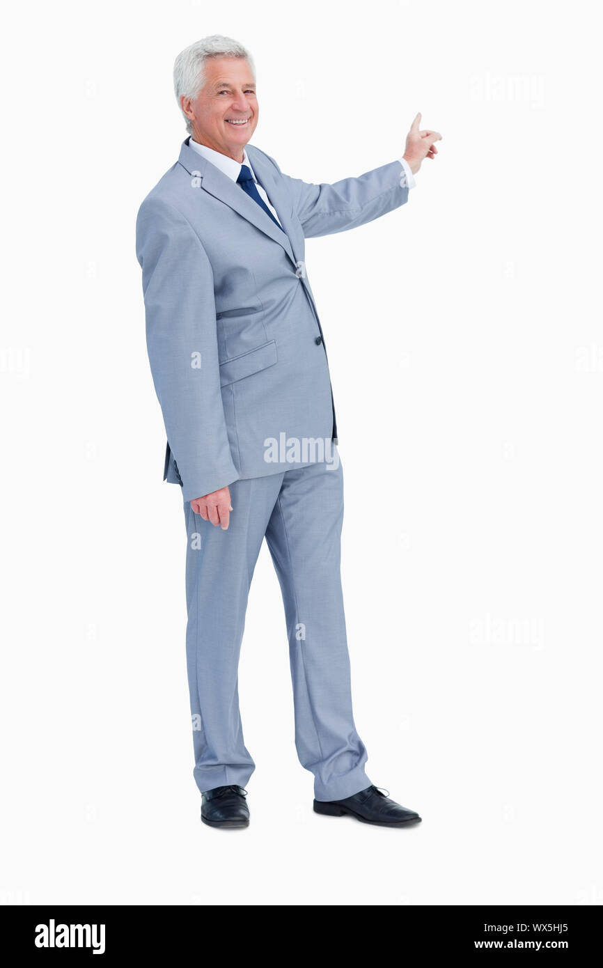 Portrait of a businessman pointing behind him against white background ...