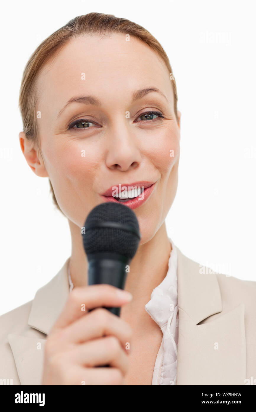 Portrait of a woman in a suit speaking with a microphone against white ...