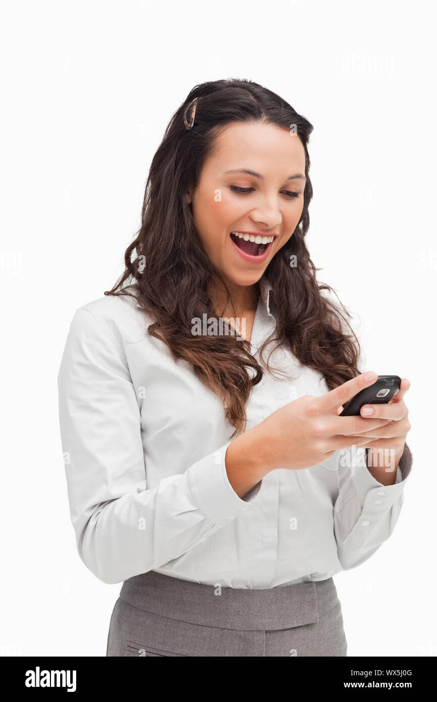 Happy brunette looking her text message against white background Stock ...
