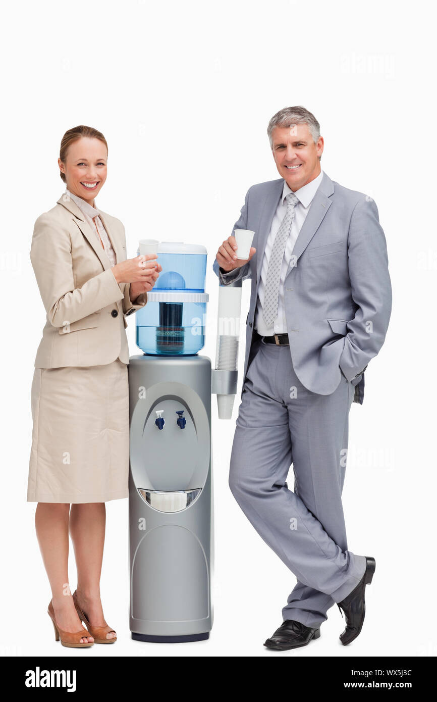 Portrait of smiling business people next to the water dispenser against ...