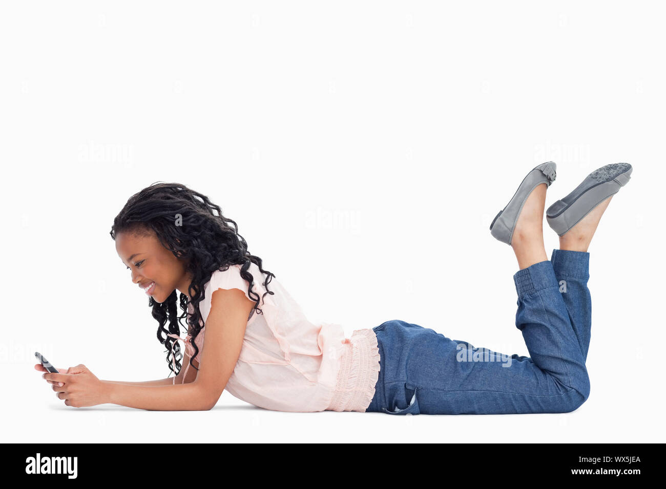 A young woman is lying on the ground texting off her mobile phone ...