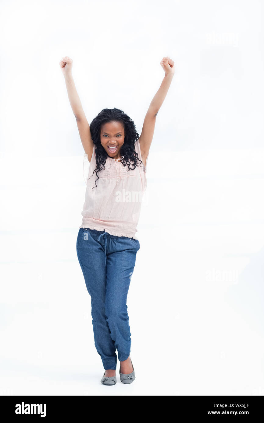 A laughing young woman is standing with her arms held up against a ...