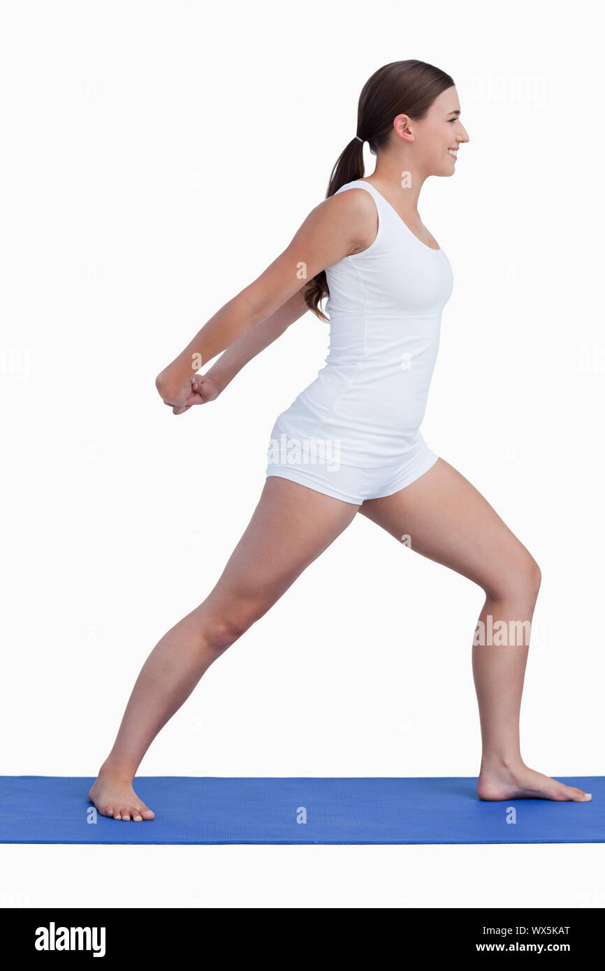 Happy woman stretching her arms while standing upright against a white ...