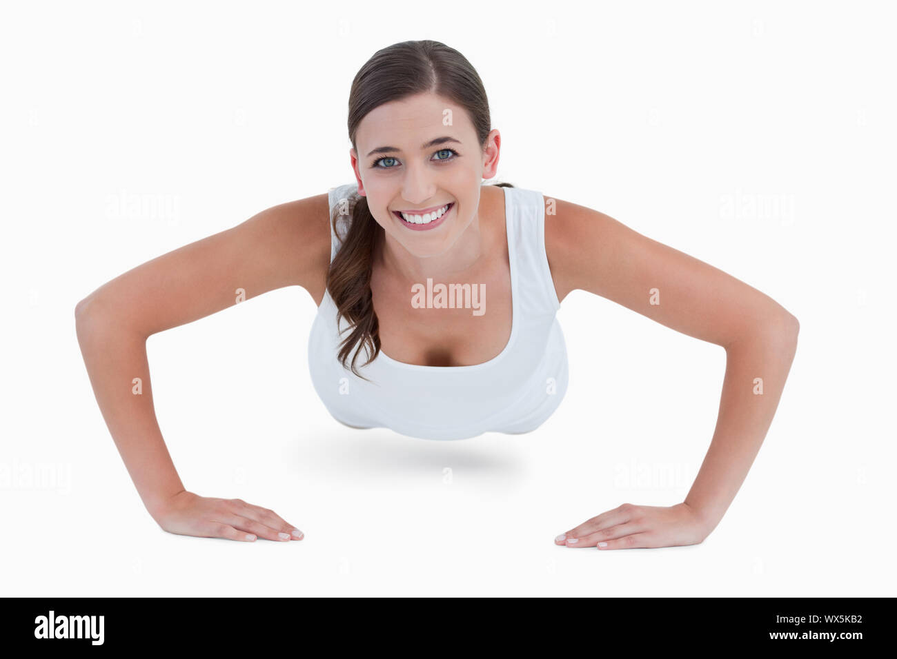 Smiling woman doing a push-up against a white background Stock Photo ...