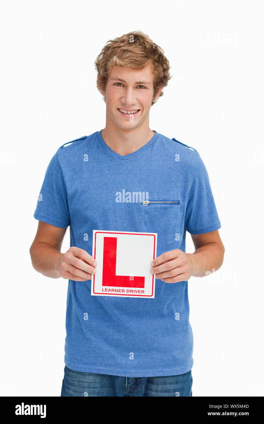 Young blond man holding a learner driver sign against white background ...