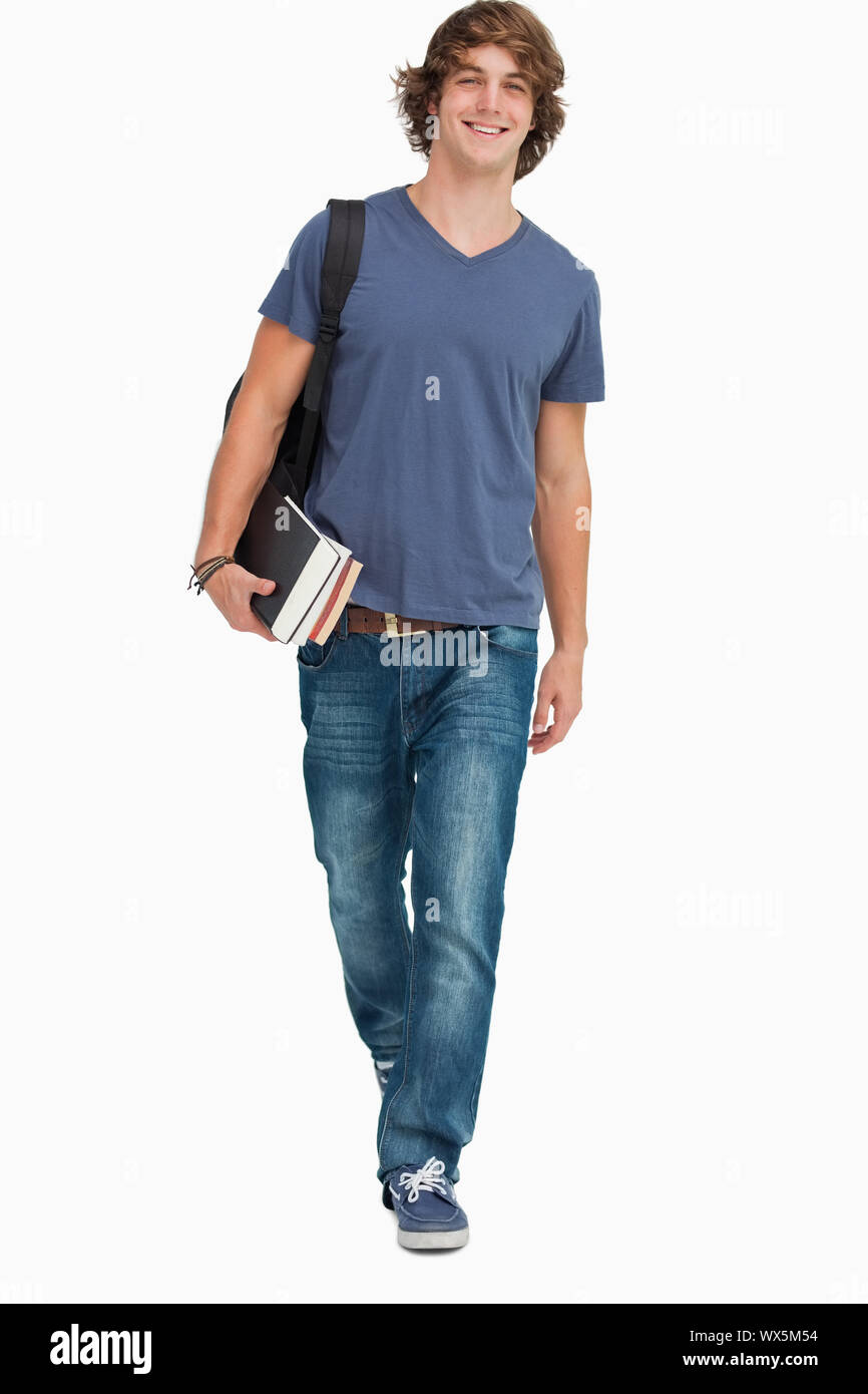 Front view of a student walking with a backpack and books against white ...