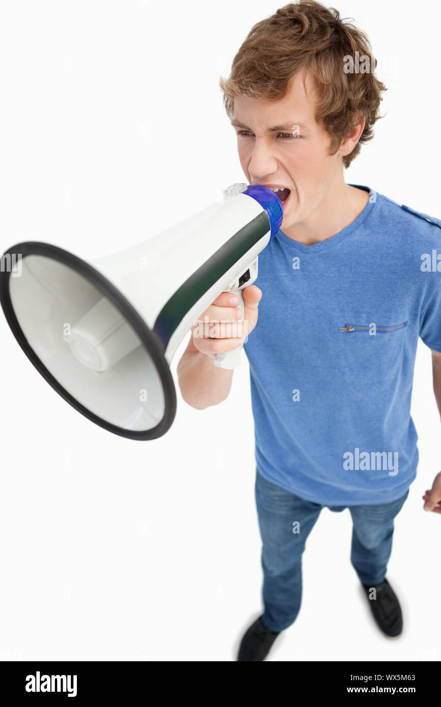 Fisheye view of a male student using a loudspeaker against white ...