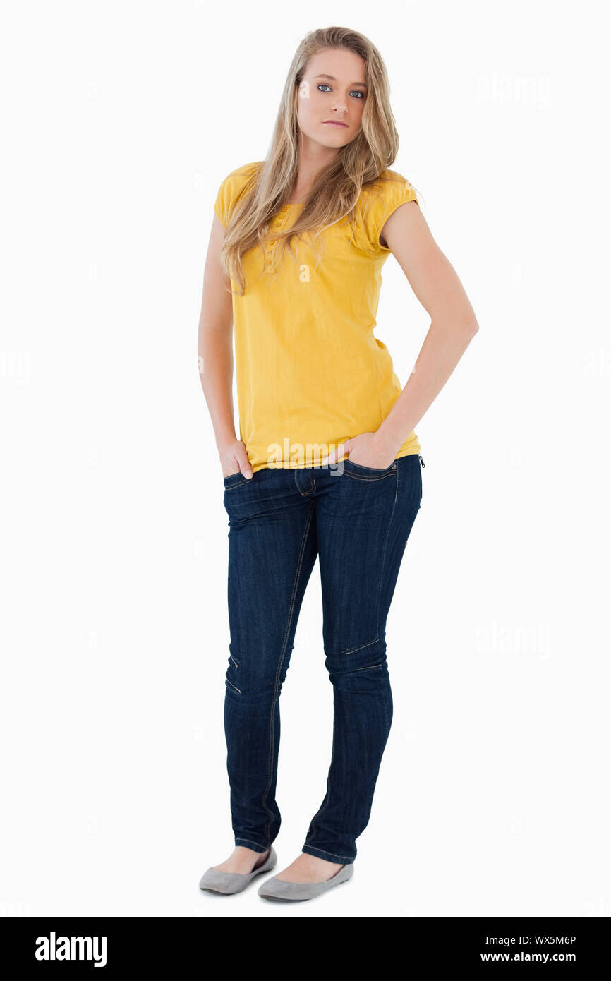 Young woman posing hands in the pockets with a yellow shirt against ...