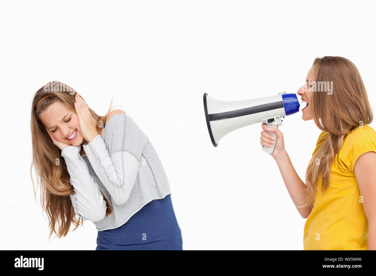 Blonde student using a loudspeaker on a other girl against white ...