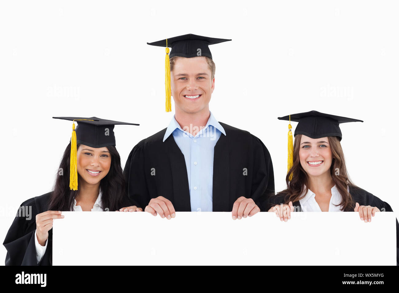 Three graduates holding a blank poster in their hands as they smile and ...