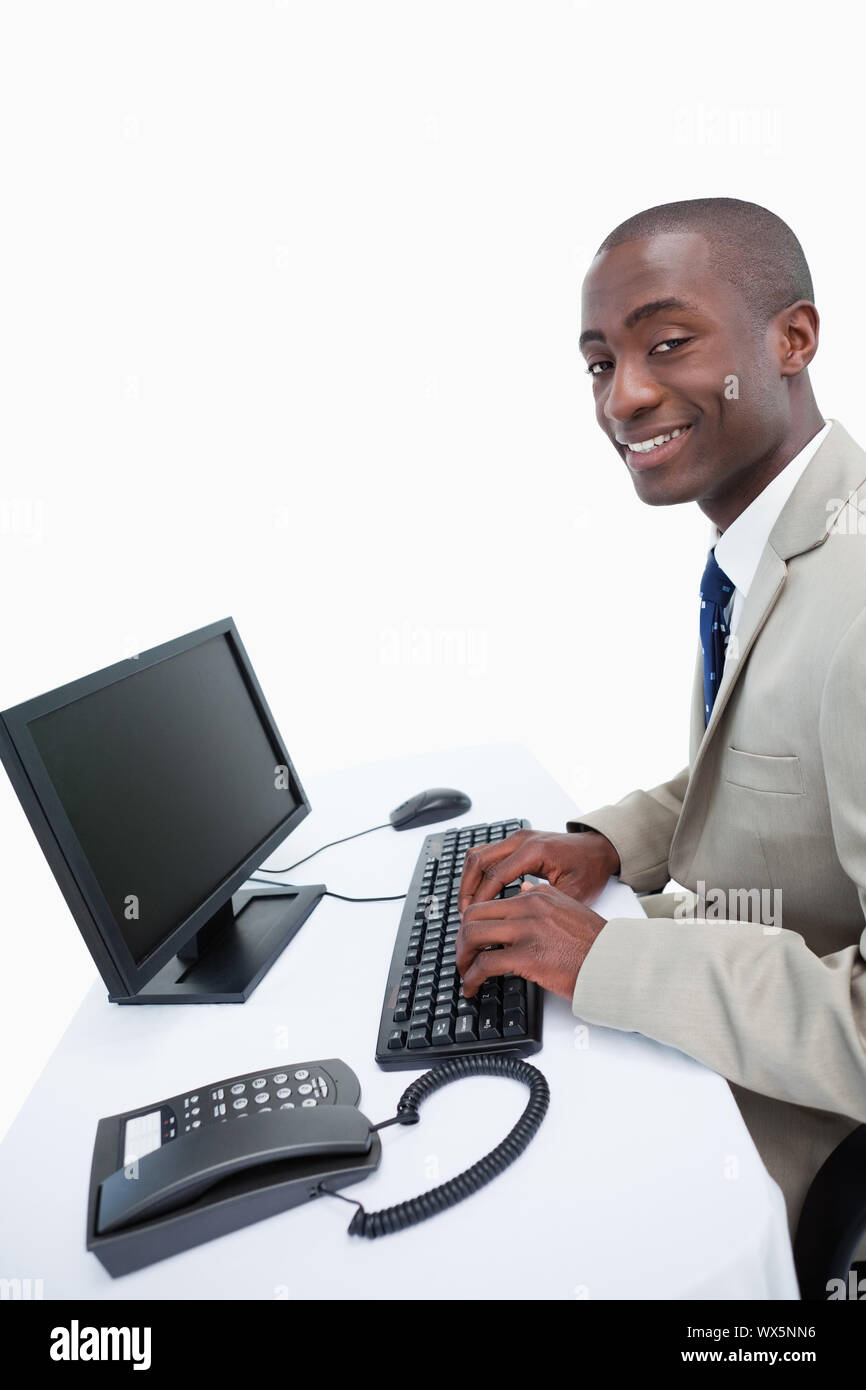 Side view of a smiling businessman using a computer against a white ...
