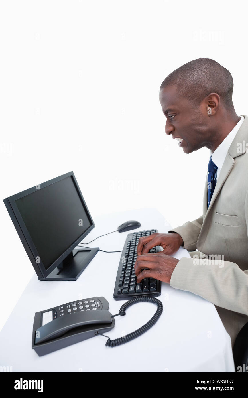 Side view of an angry businessman using a computer against a white ...