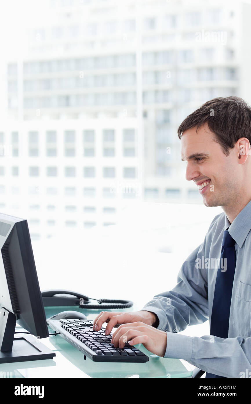 Side view of a smiling office worker using a monitor in his office ...