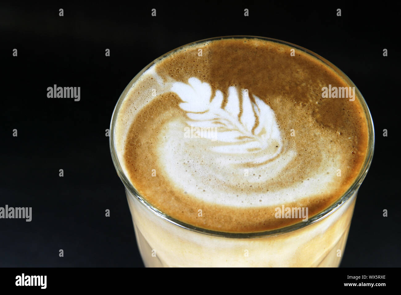A double latte in a tall latte glass with latte art Stock Photo - Alamy
