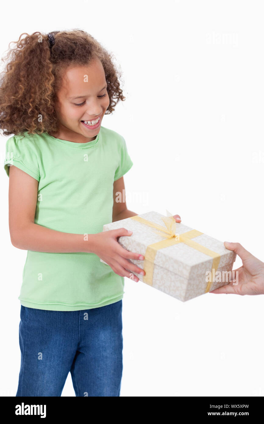 Portrait of a young girl receiving a present against a white background ...