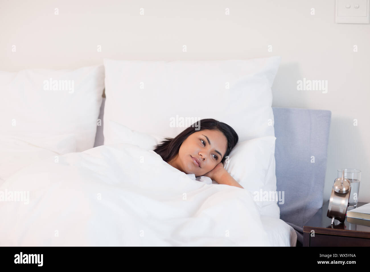 Young woman staring at alarm clock Stock Photo - Alamy