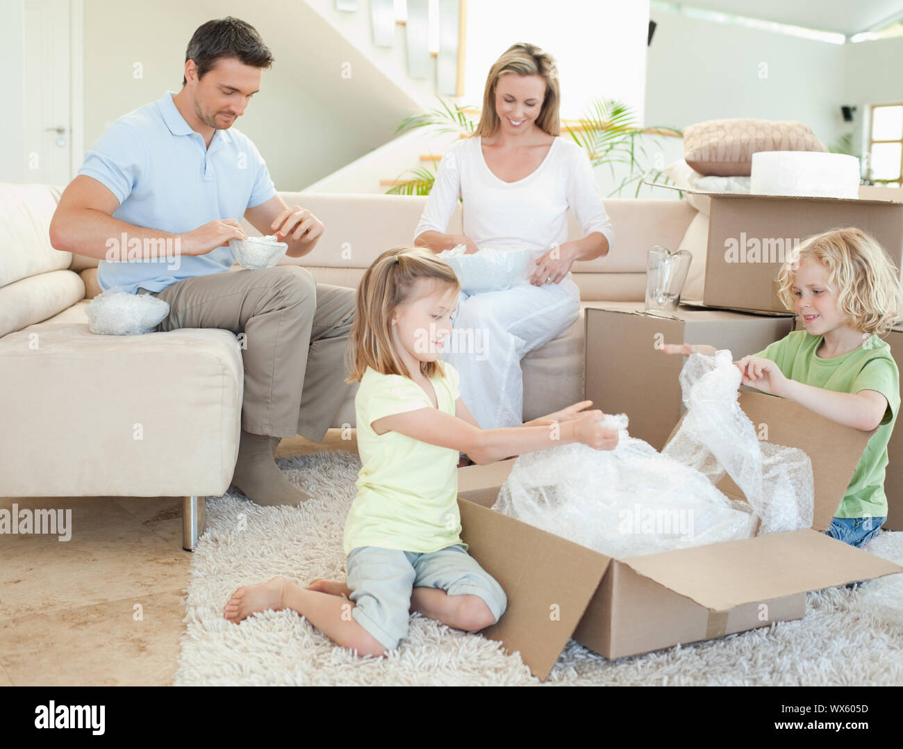 Family unpacking cardboard box together Stock Photo - Alamy