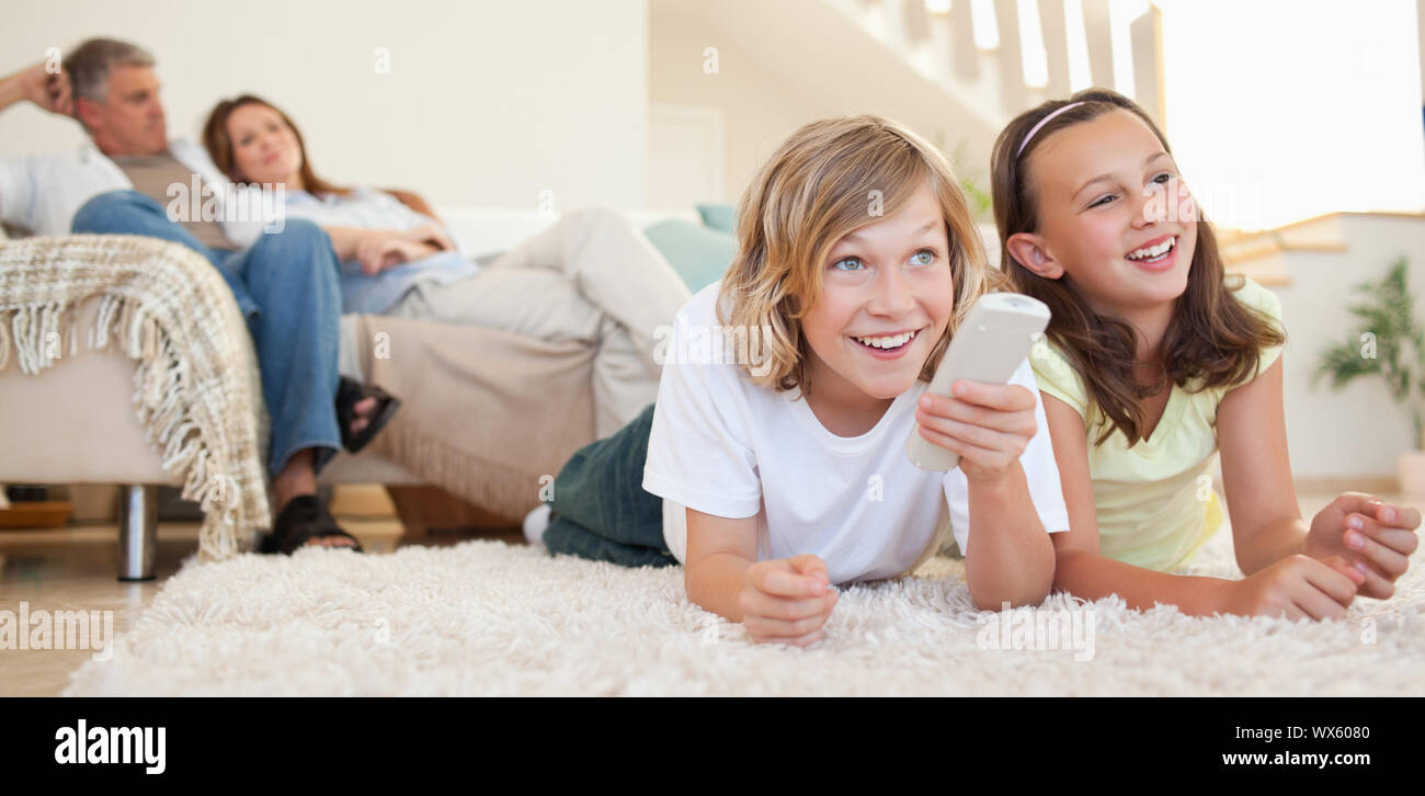 Siblings lying on the floor watching tv together Stock Photo - Alamy