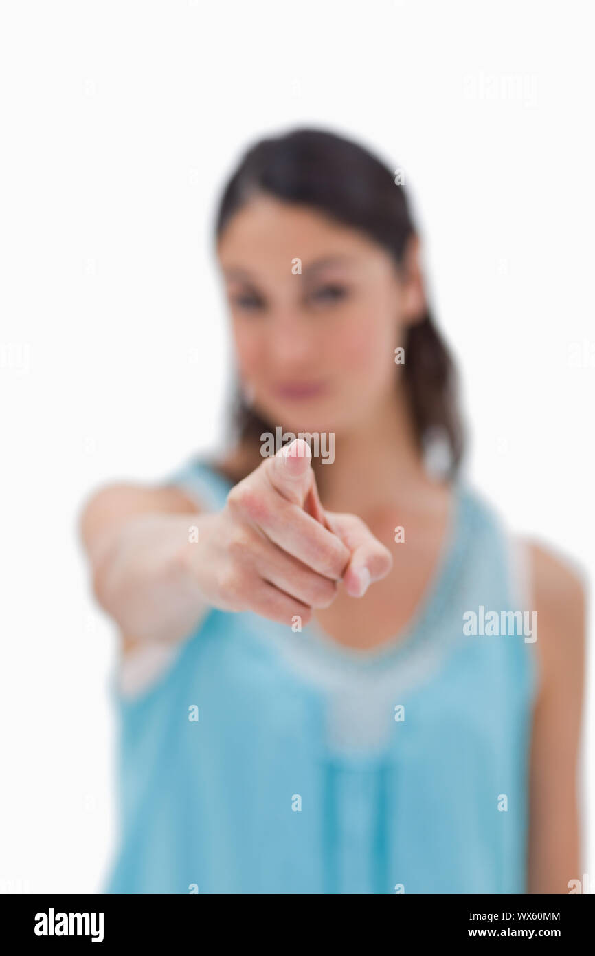 Portrait of a brunette woman pointing at the viewer against a white ...
