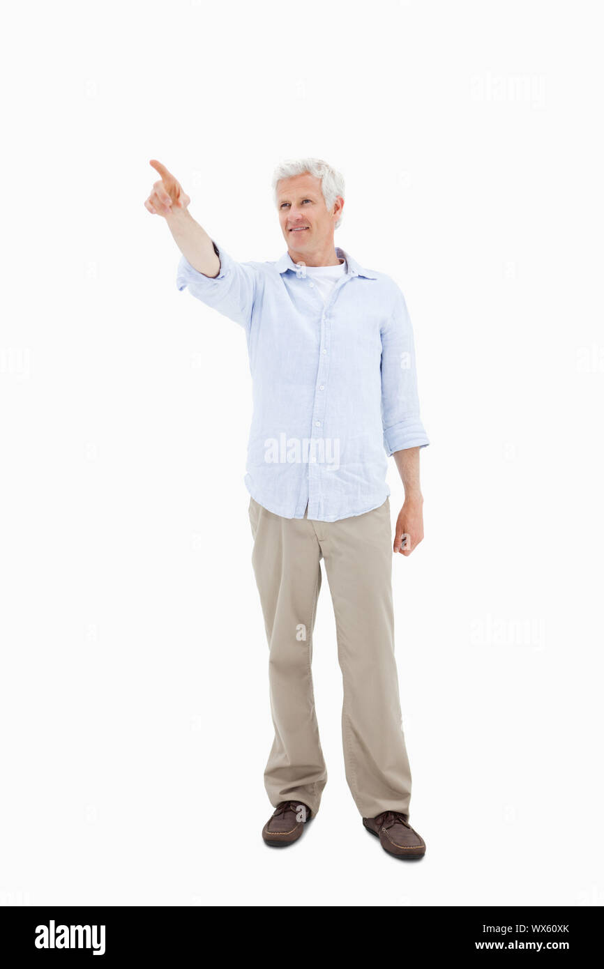 Portrait of a handsome mature man pointing at something against a white ...