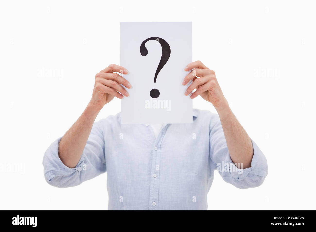 Portrait of a man hiding his face behind a question mark against a ...