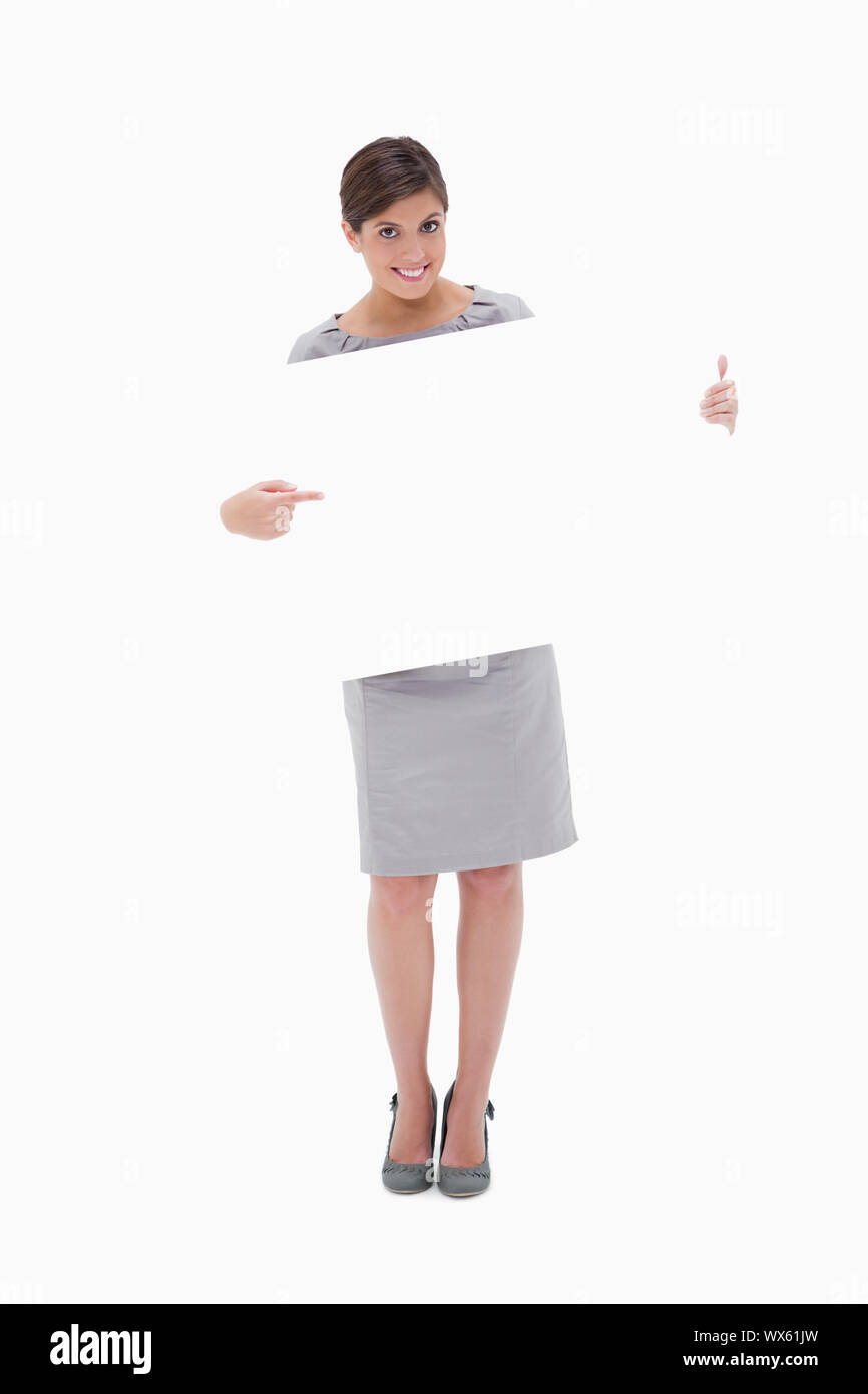 Smiling woman pointing at blank sign in her hands against a white ...