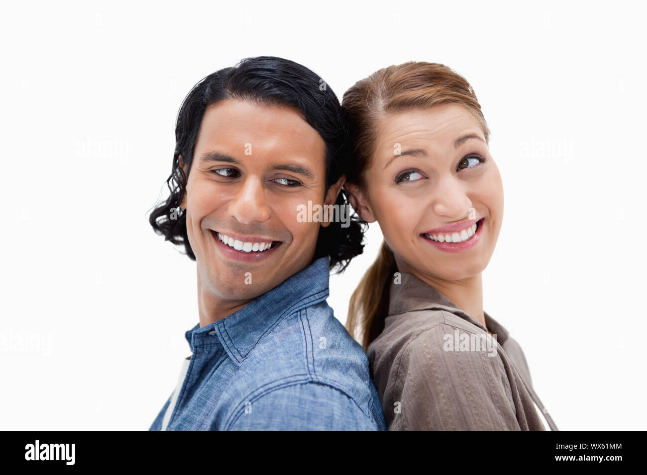 Side view of happy couple standing back to back against a white ...