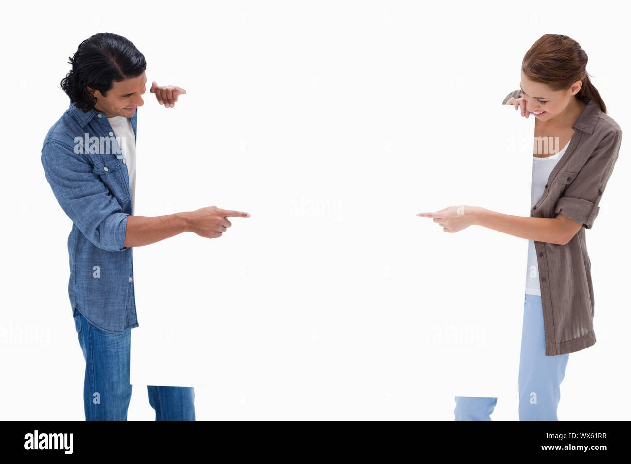 Couple looking and pointing at blank sign in their hands against a ...