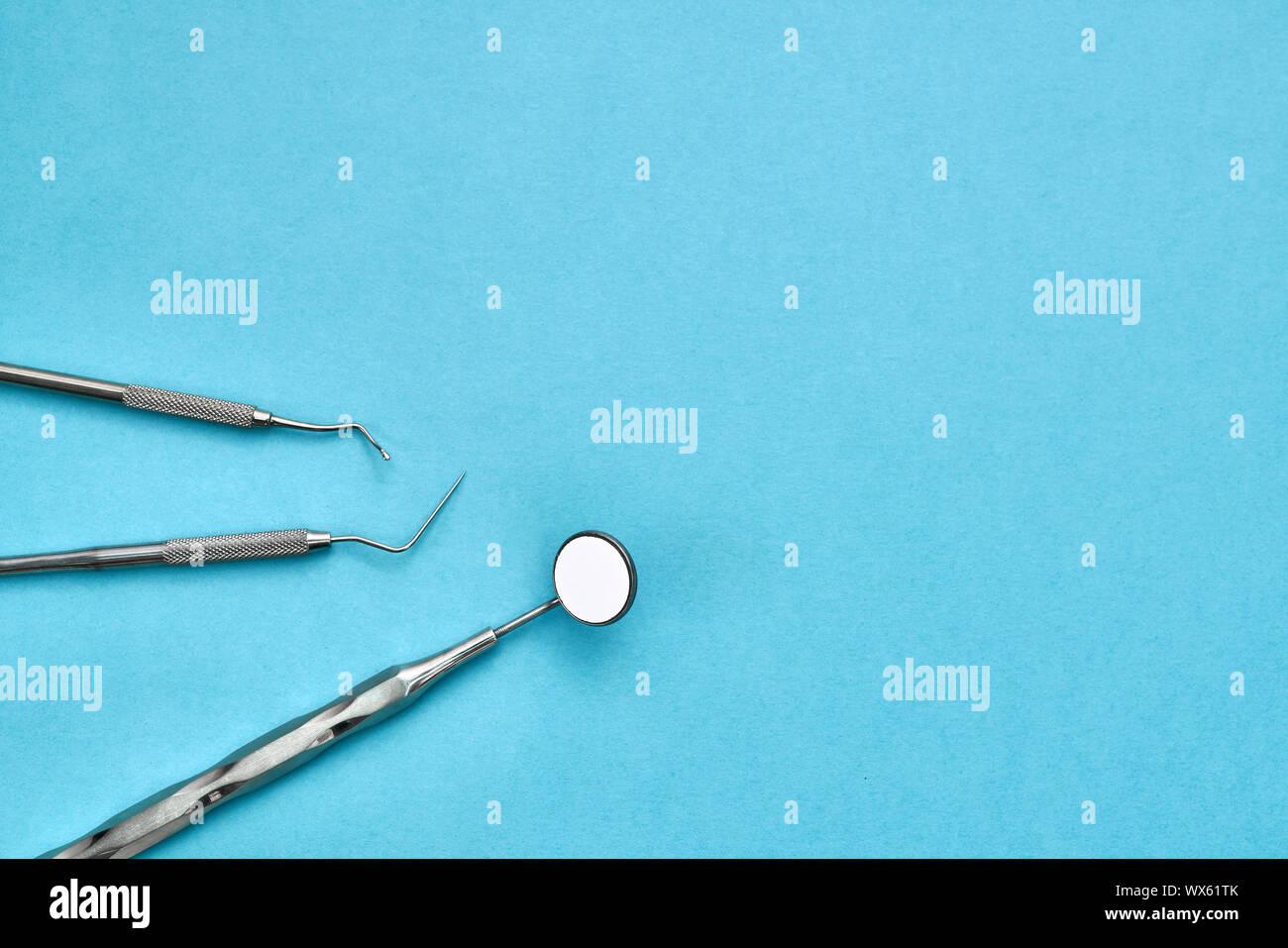 Few steel dental instruments: mirror, probe and a scraper on the blue ...