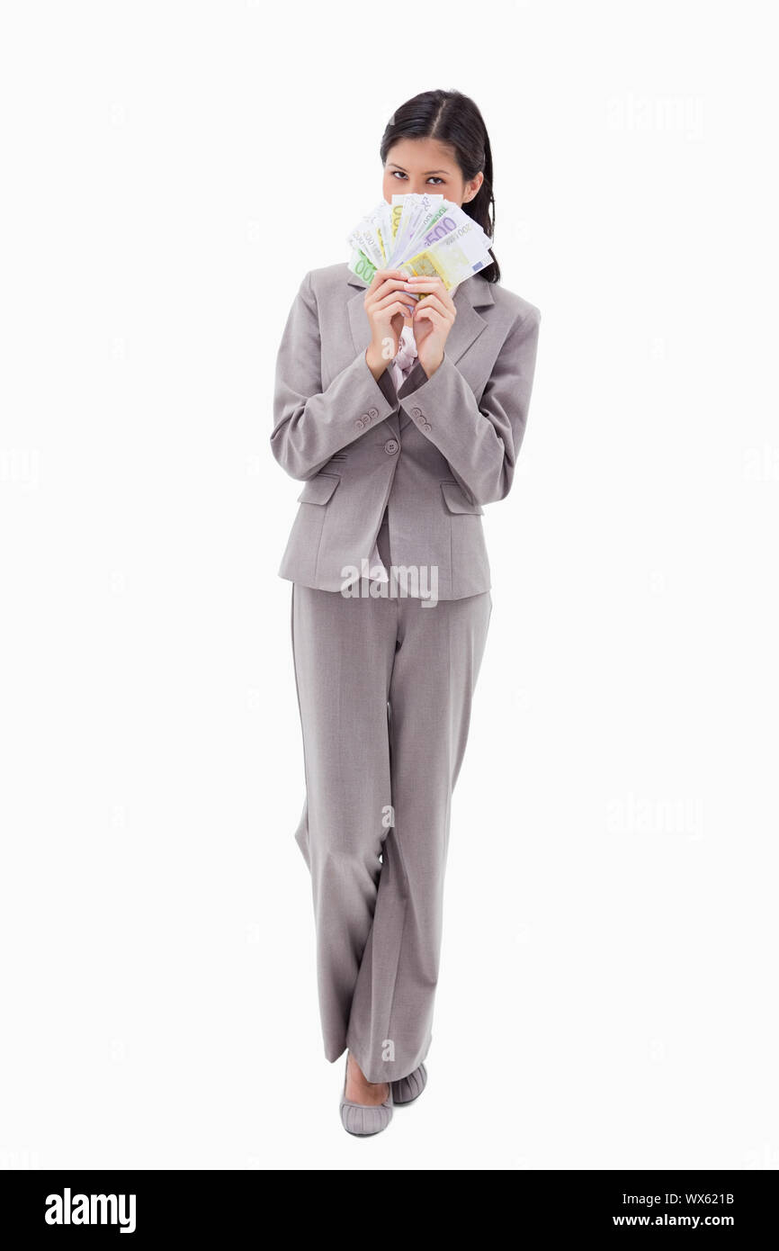 Businesswoman hiding face behind bank notes against a white background ...