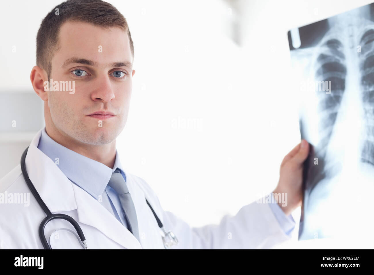 Serious looking doctor showing x-ray image to patient Stock Photo - Alamy