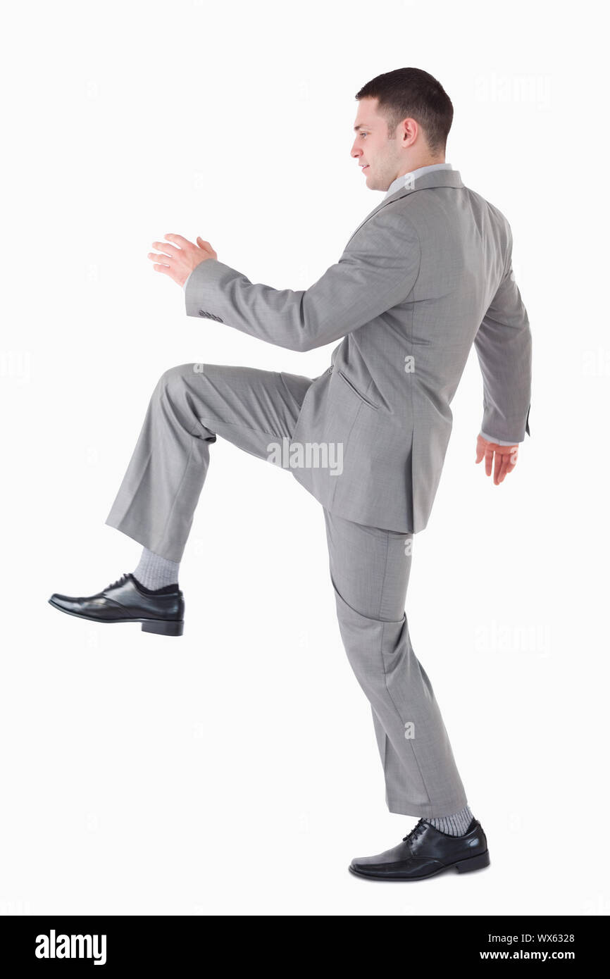 Portrait of a businessman lifting his leg up against a white background ...