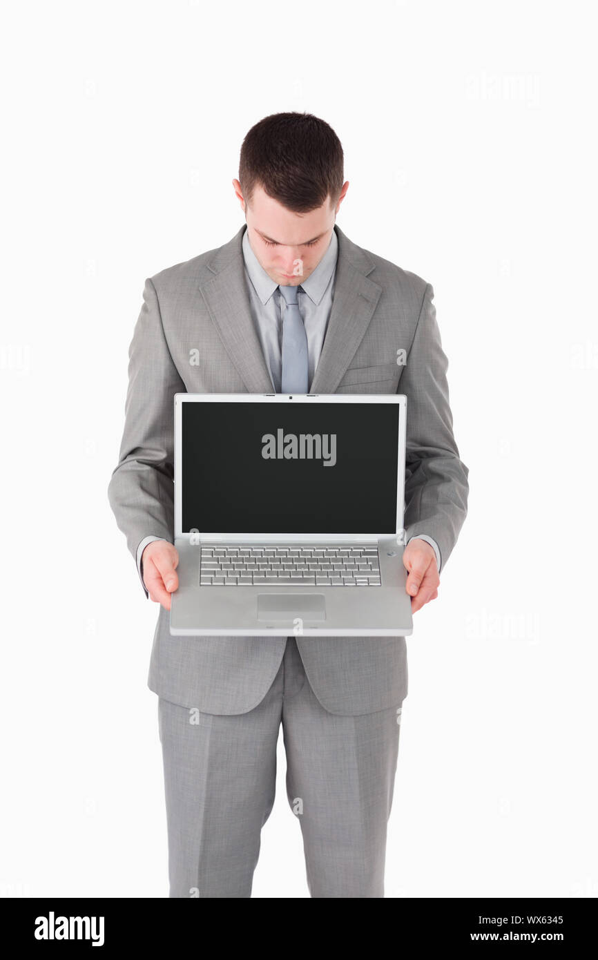 Portrait of a businessman looking at a laptop's screen against a white ...