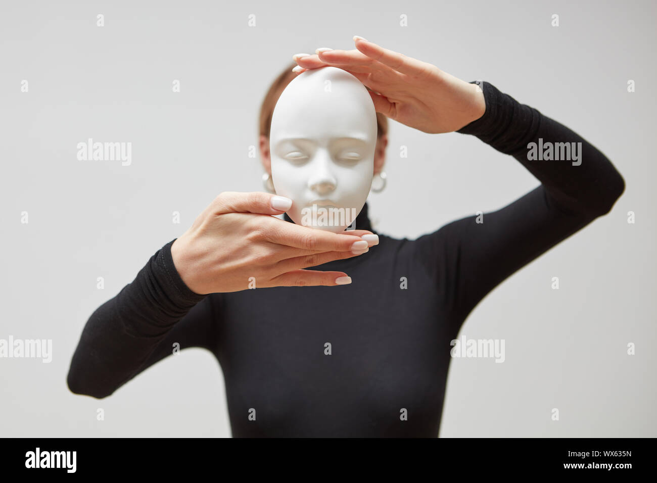 Woman's hands hold gypsum mask. Girl in a black jumper with plaster ...