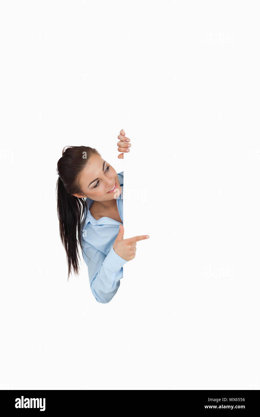 Businesswoman pointing while looking around the corner against a white ...