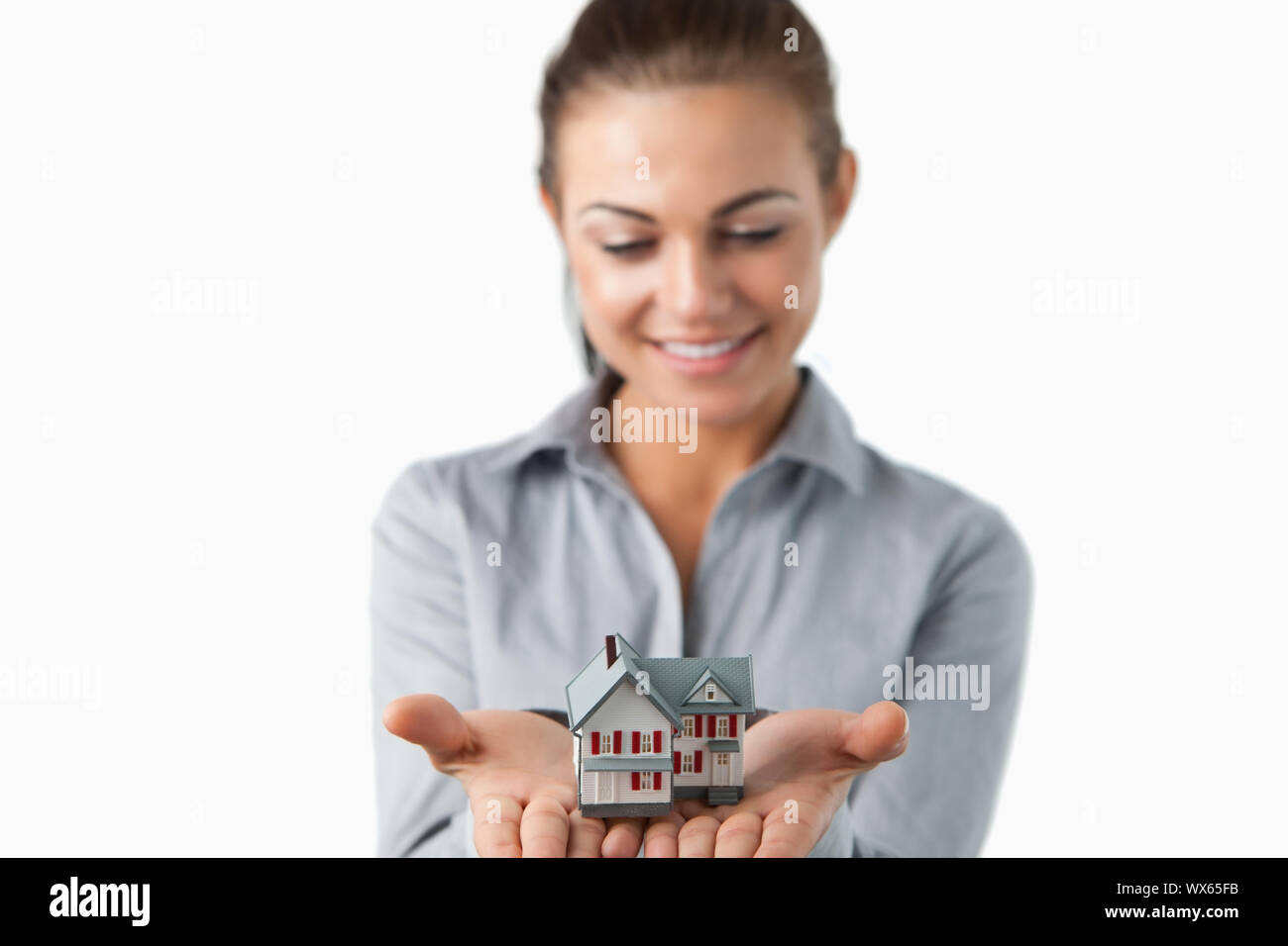 Miniature house being held by female estate agent against a white ...