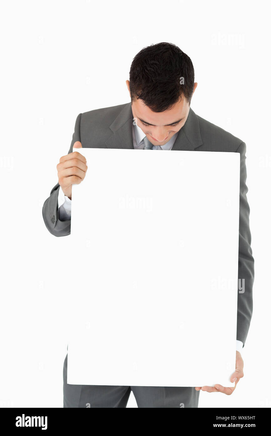 Businessman looking at sign in his hands against a white background ...