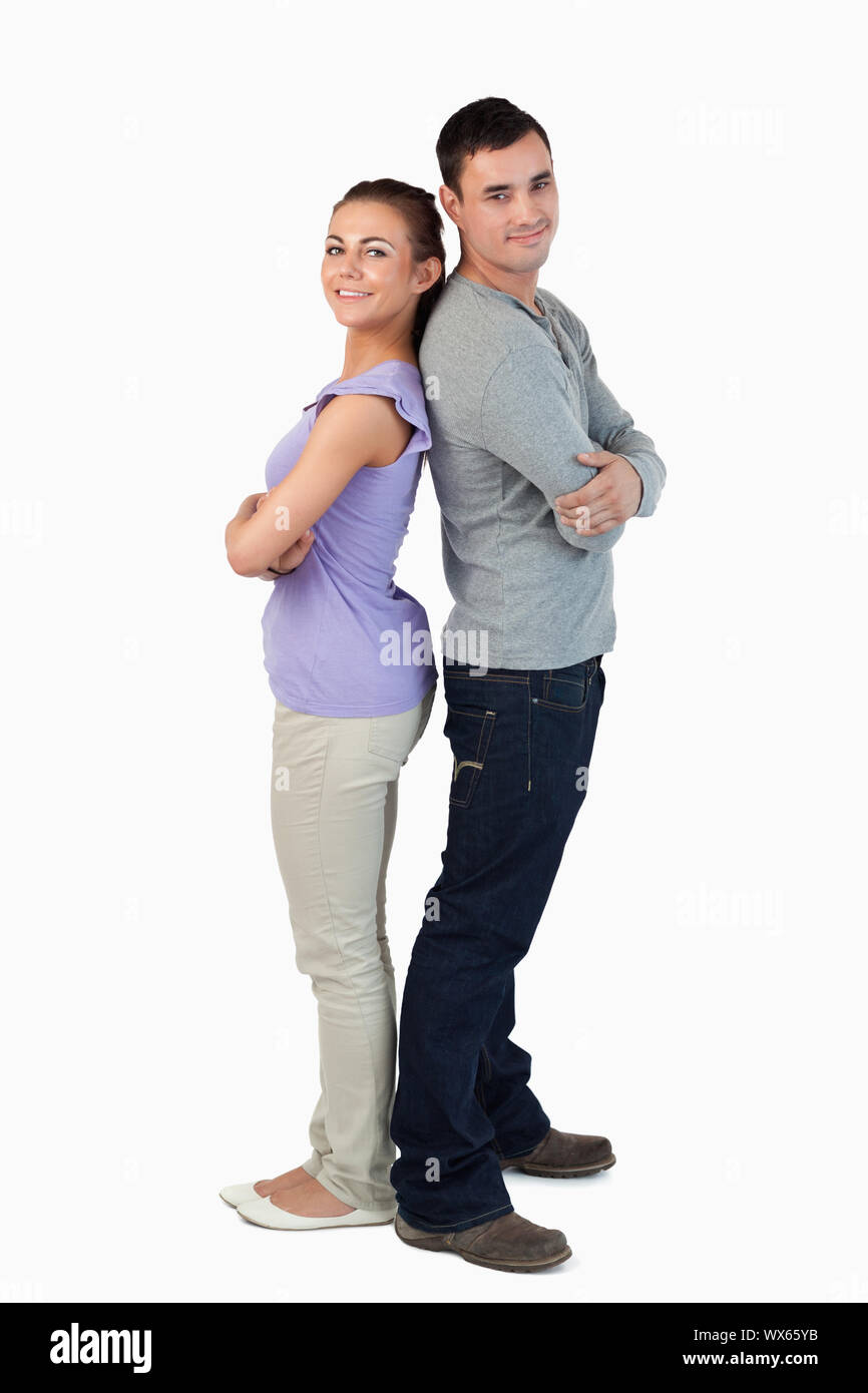 Happy young couple standing back-to-back against a white background ...