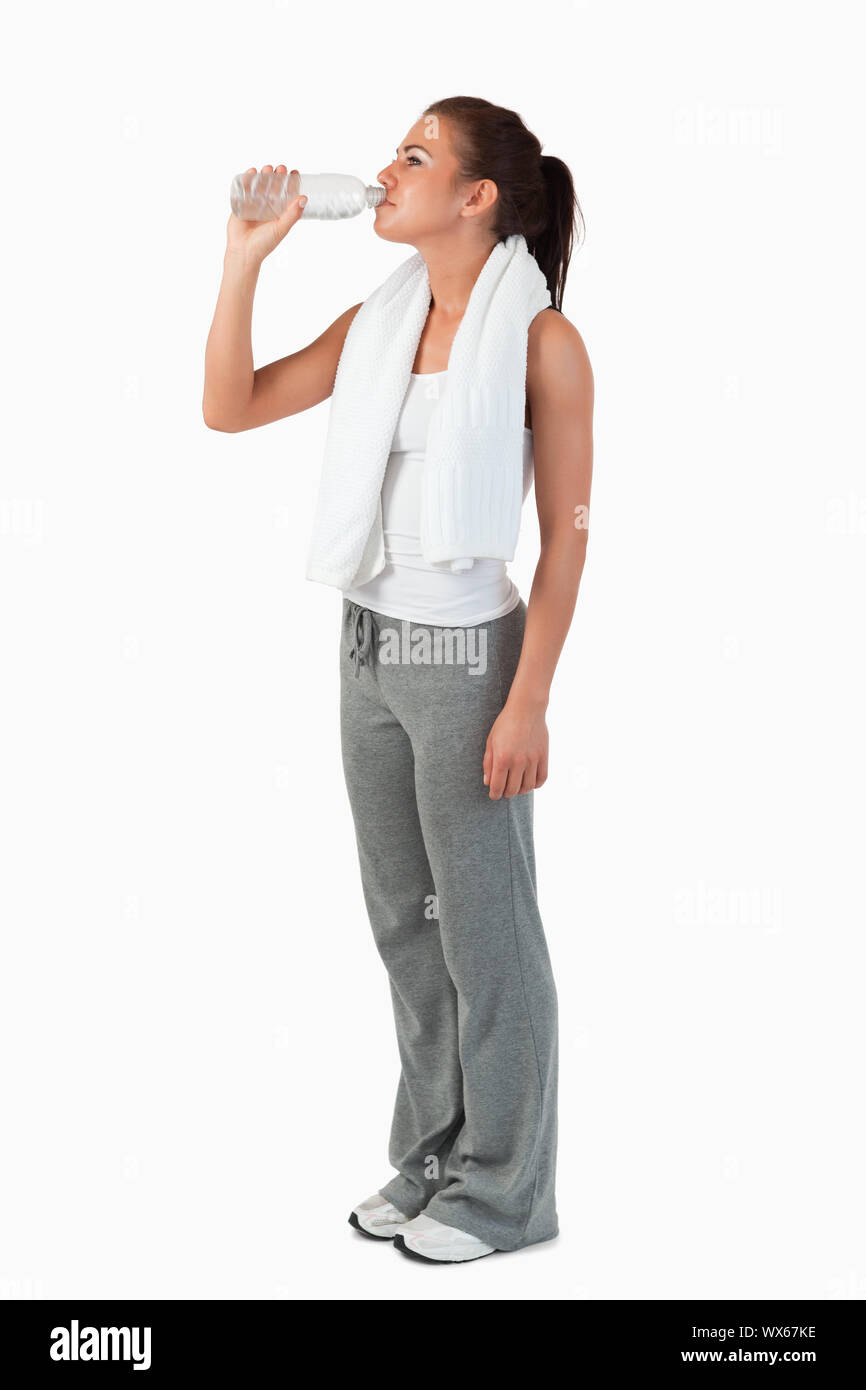 Side view of young female taking a sip of water after training against ...