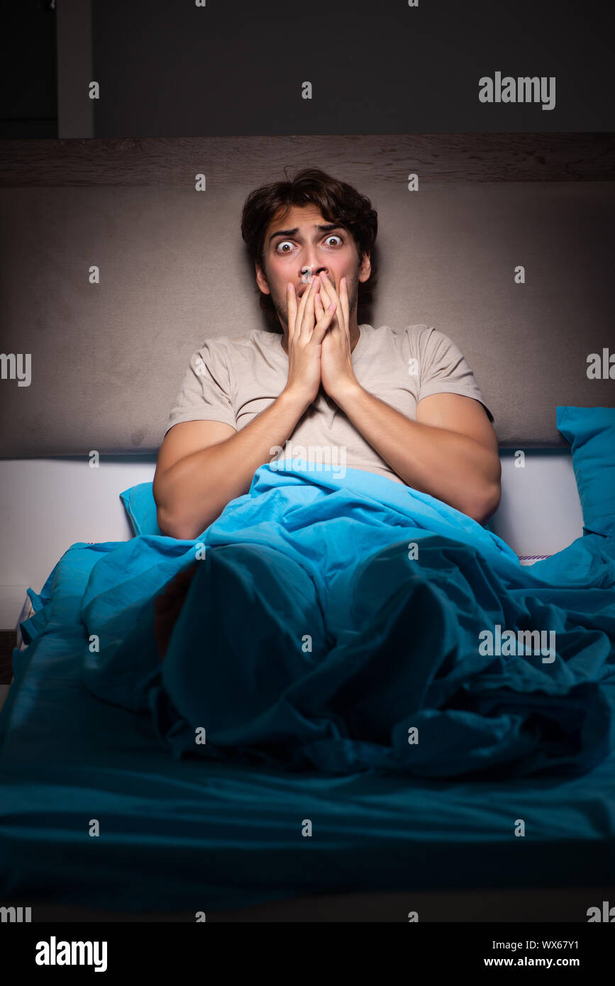 Young man scared in his bed having nightmares Stock Photo - Alamy