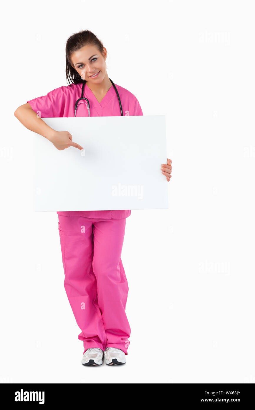 Portrait of a brunette doctor pointing at a blank panel against a white ...