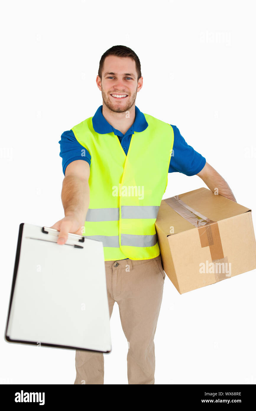 Smiling young delivery man handing over delivery note for signature ...