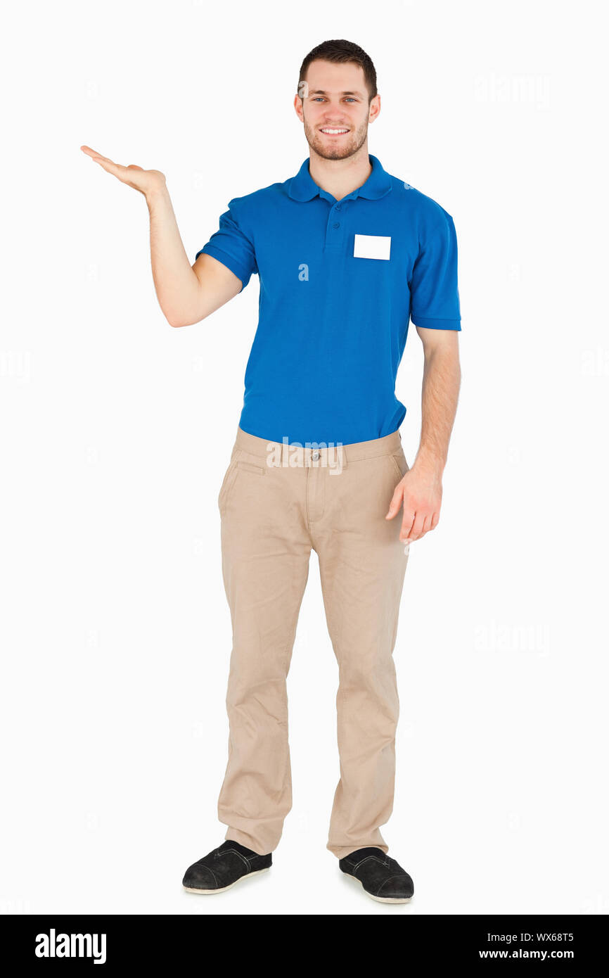 Smiling young salesman presenting in his palm against a white ...