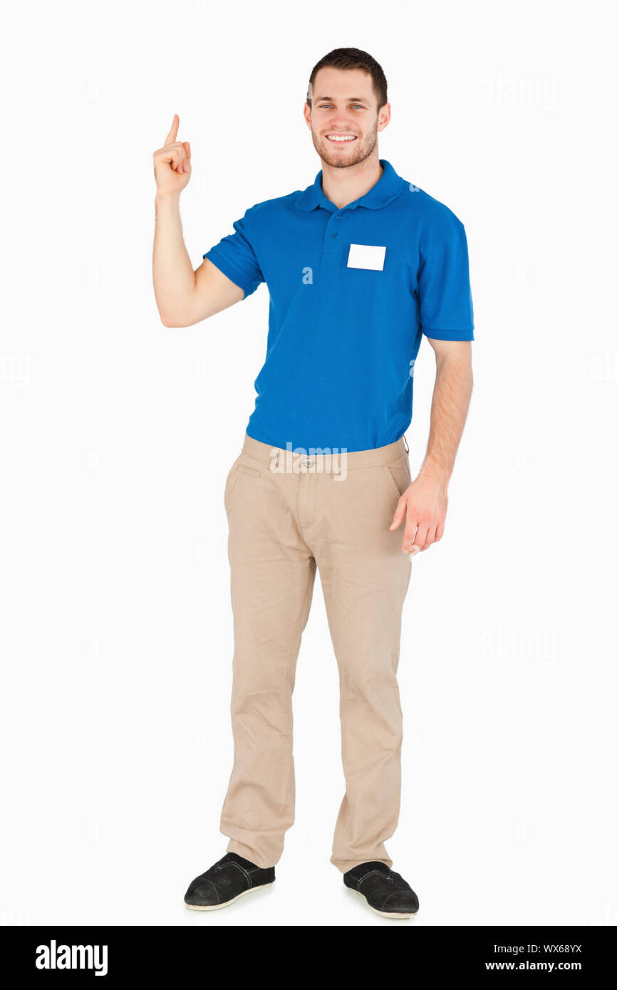 Smiling young salesman pointing upwards against a white background ...