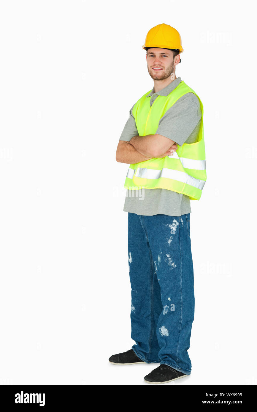 Side view of smiling young construction worker with arms folded against ...